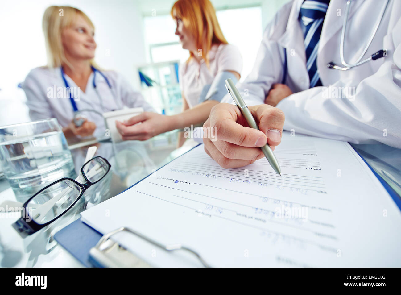 Close-up of doctor with pen filling in personal data Stock Photo - Alamy