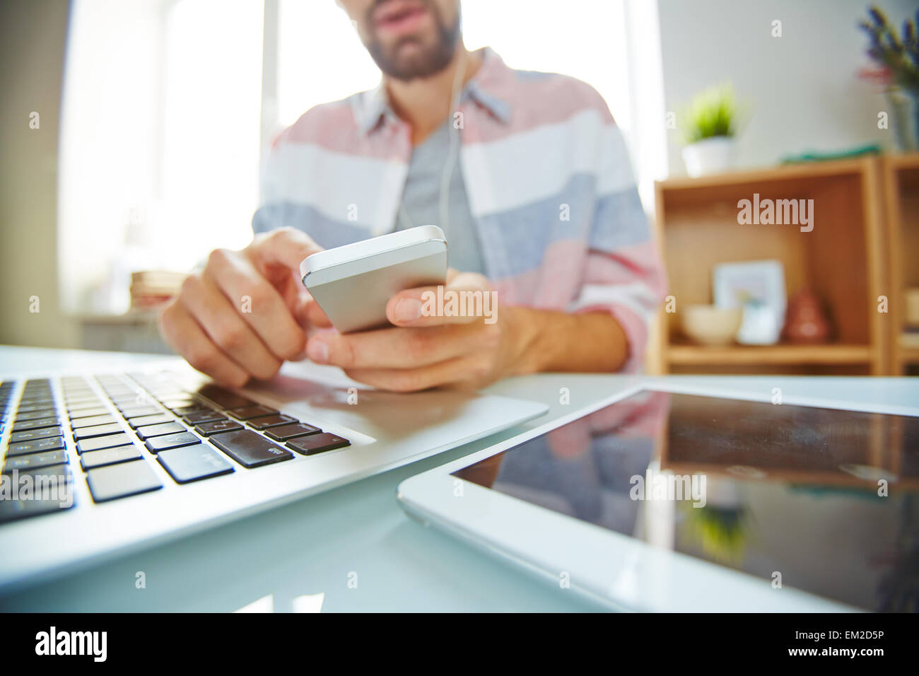 Hands of young man using smartphone over laptop keypad Stock Photo - Alamy