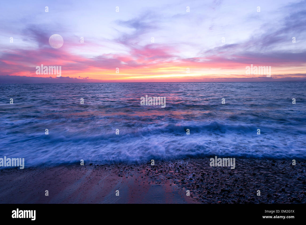 Moon rises over a colorful moon ocean beach sunset Stock Photo - Alamy