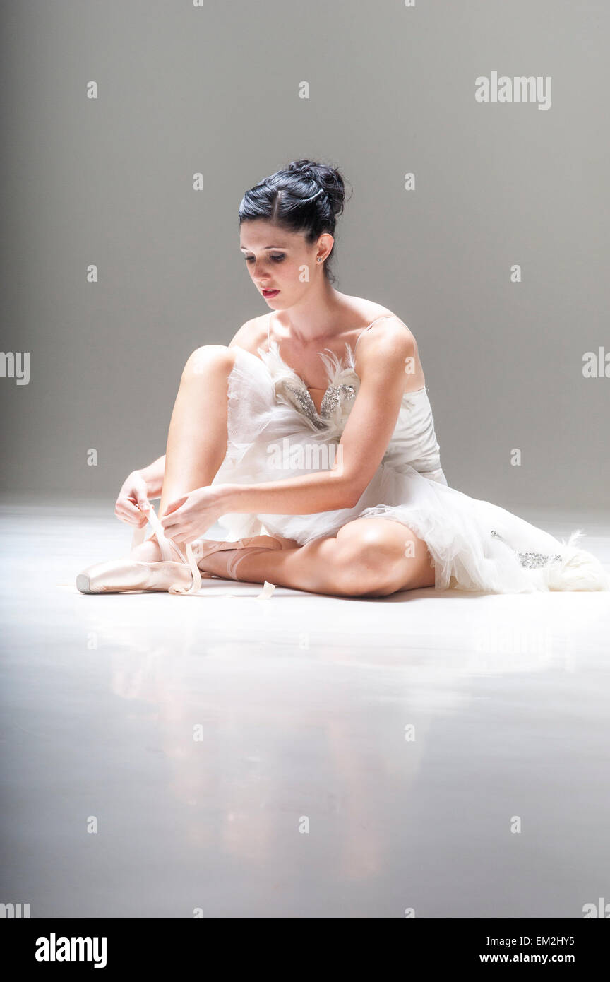 Young attractive ballerina sitting on the floor working with her ...