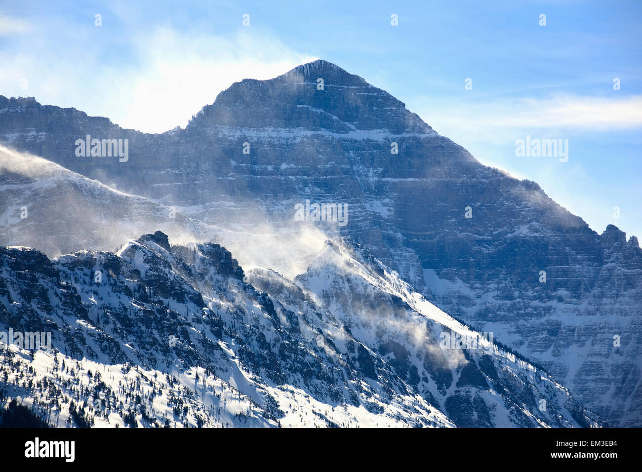 Mountain Peaks With Blowing Snow Over Ridges And Blue Sky; Waterton ...