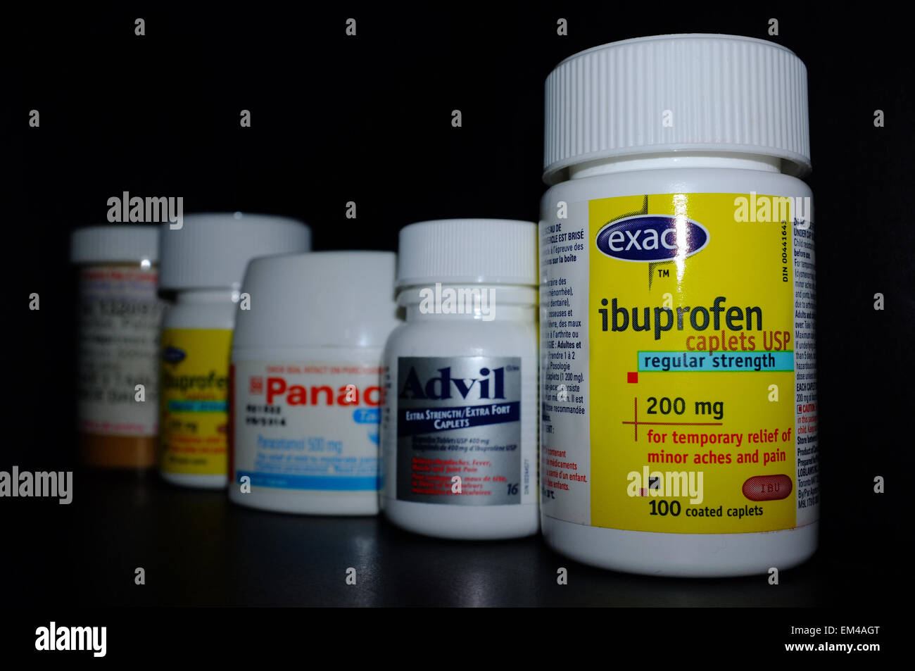 Several painkiller bottles photographed against a black background ...