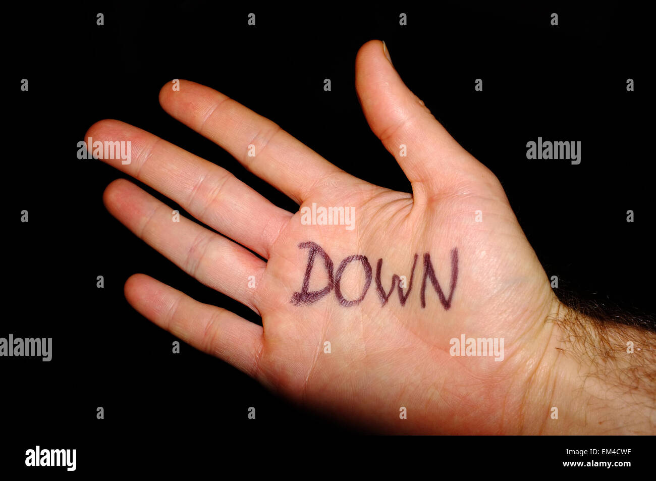 Down written on a white man's hand photographed against a black ...