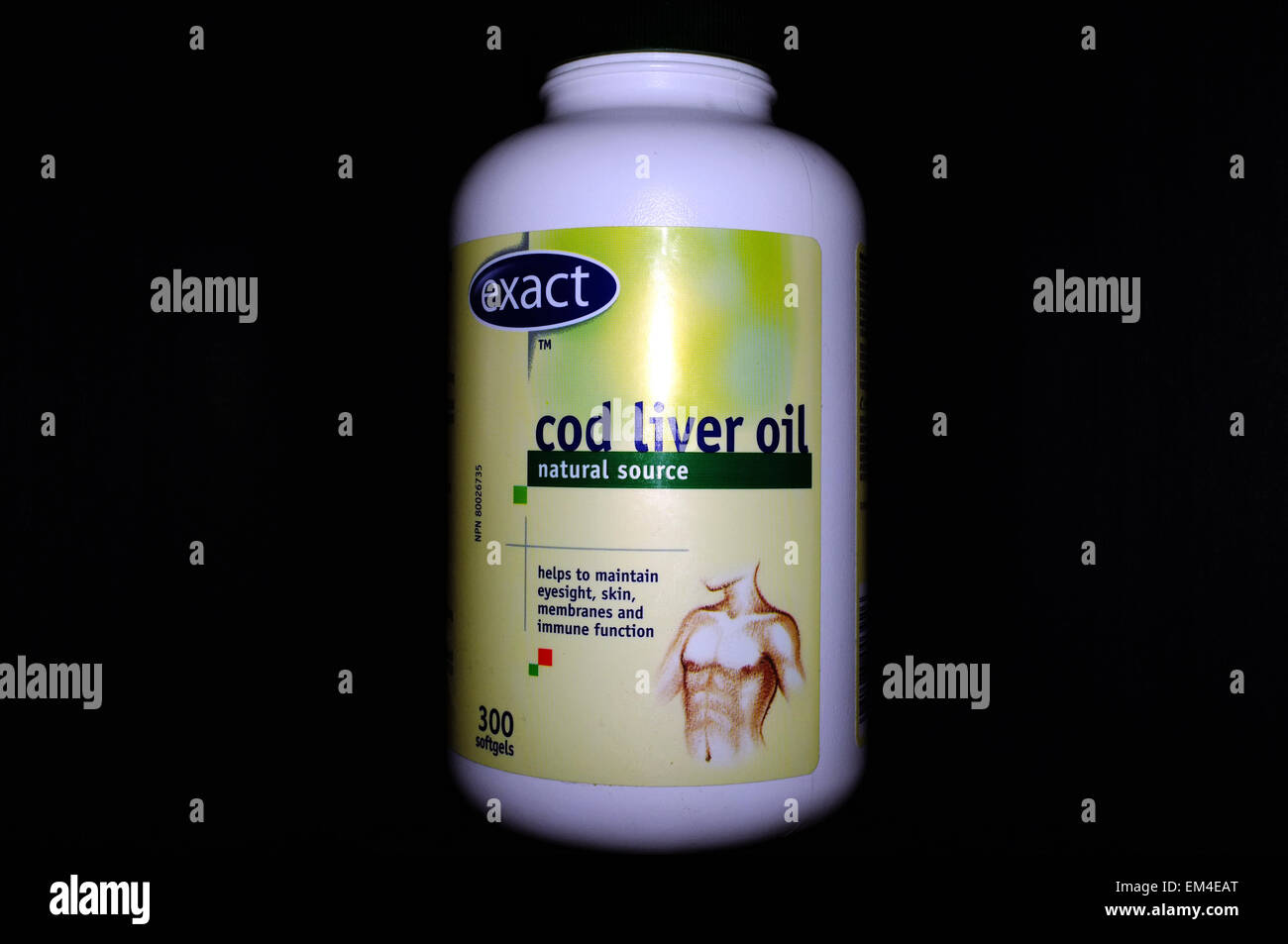 A bottle of cod liver oil tablets photographed against a black ...