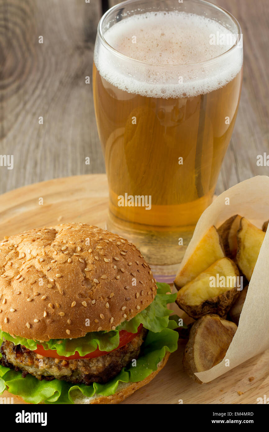 Shot of burger, roasted potato wedges and glass of beer Stock Photo - Alamy