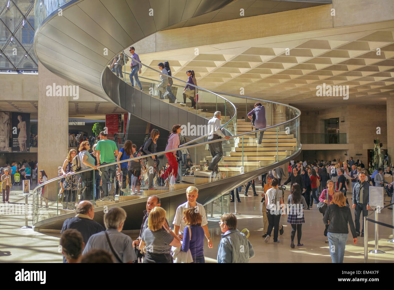 Visitors walking inside the airy entry hall of the Louvre museum in ...