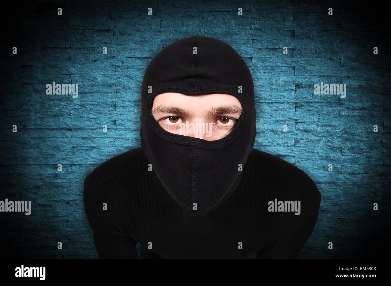 robber in mask on a blue wall background Stock Photo - Alamy