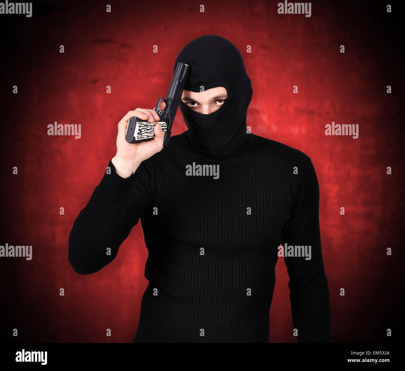 terrorist with gun on red wall background Stock Photo - Alamy