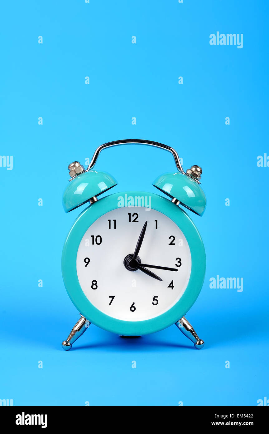 old style alarm clock isolated on blue Stock Photo - Alamy