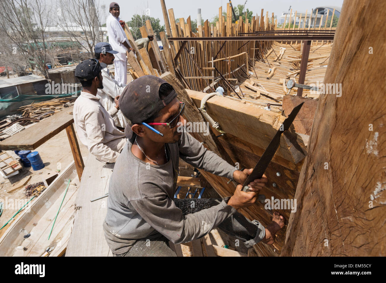 Craftsmen building a traditional wooden dhow cargo ship in shipyard ...