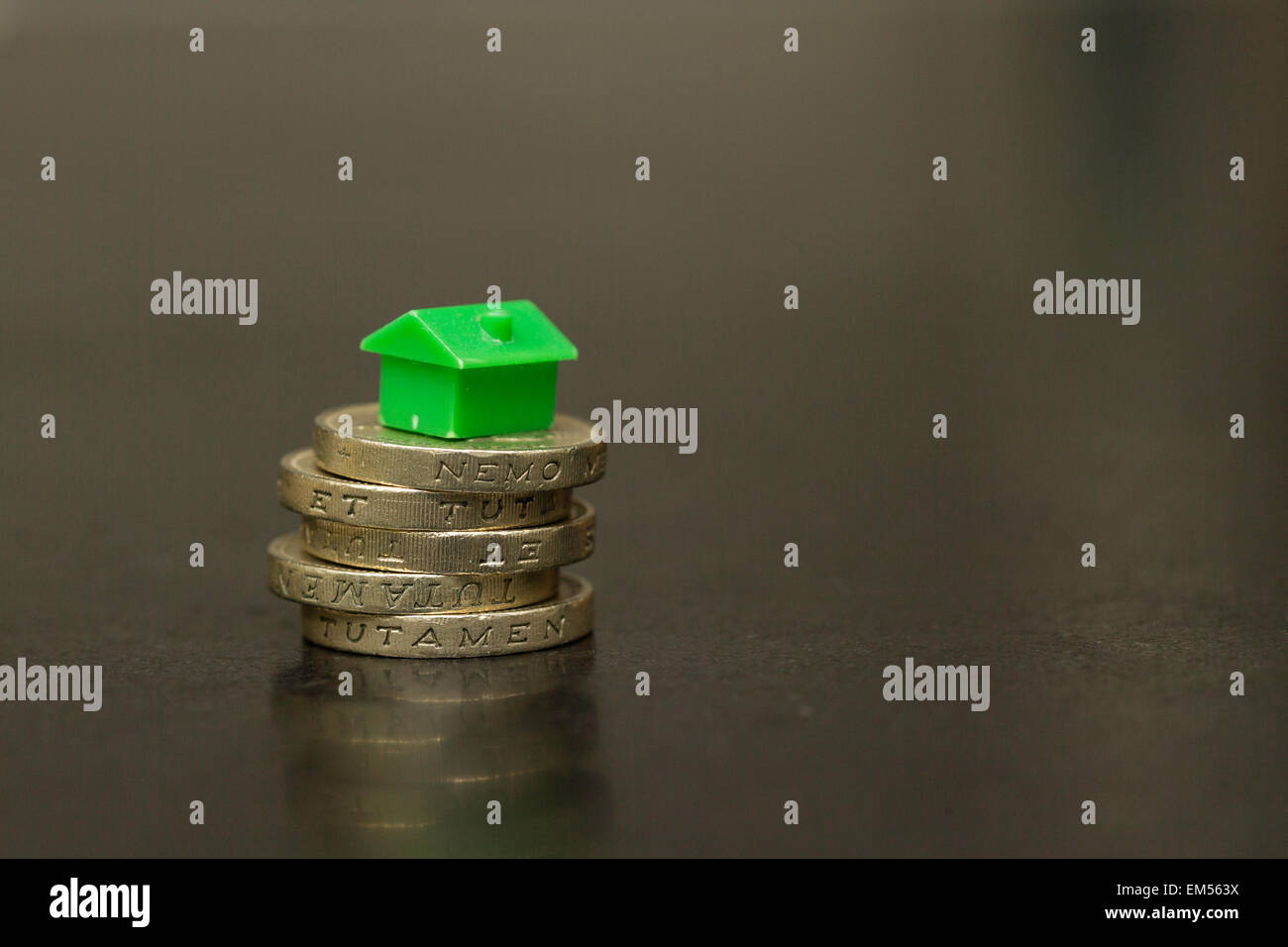 A pile of British pound coins with a monopoly house Stock Photo - Alamy