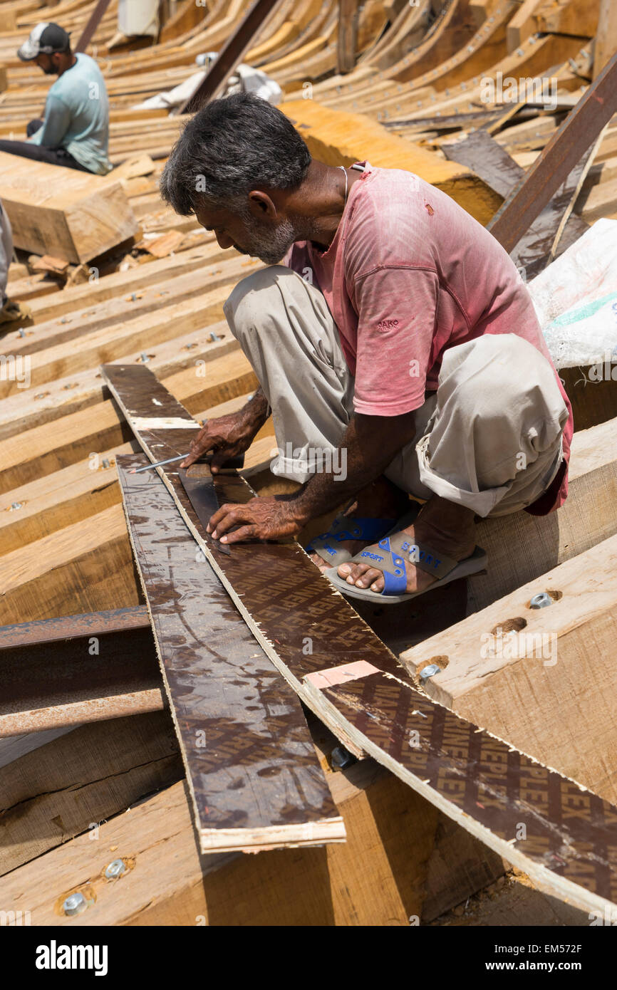 Craftsmen building a traditional wooden dhow cargo ship in shipyard ...