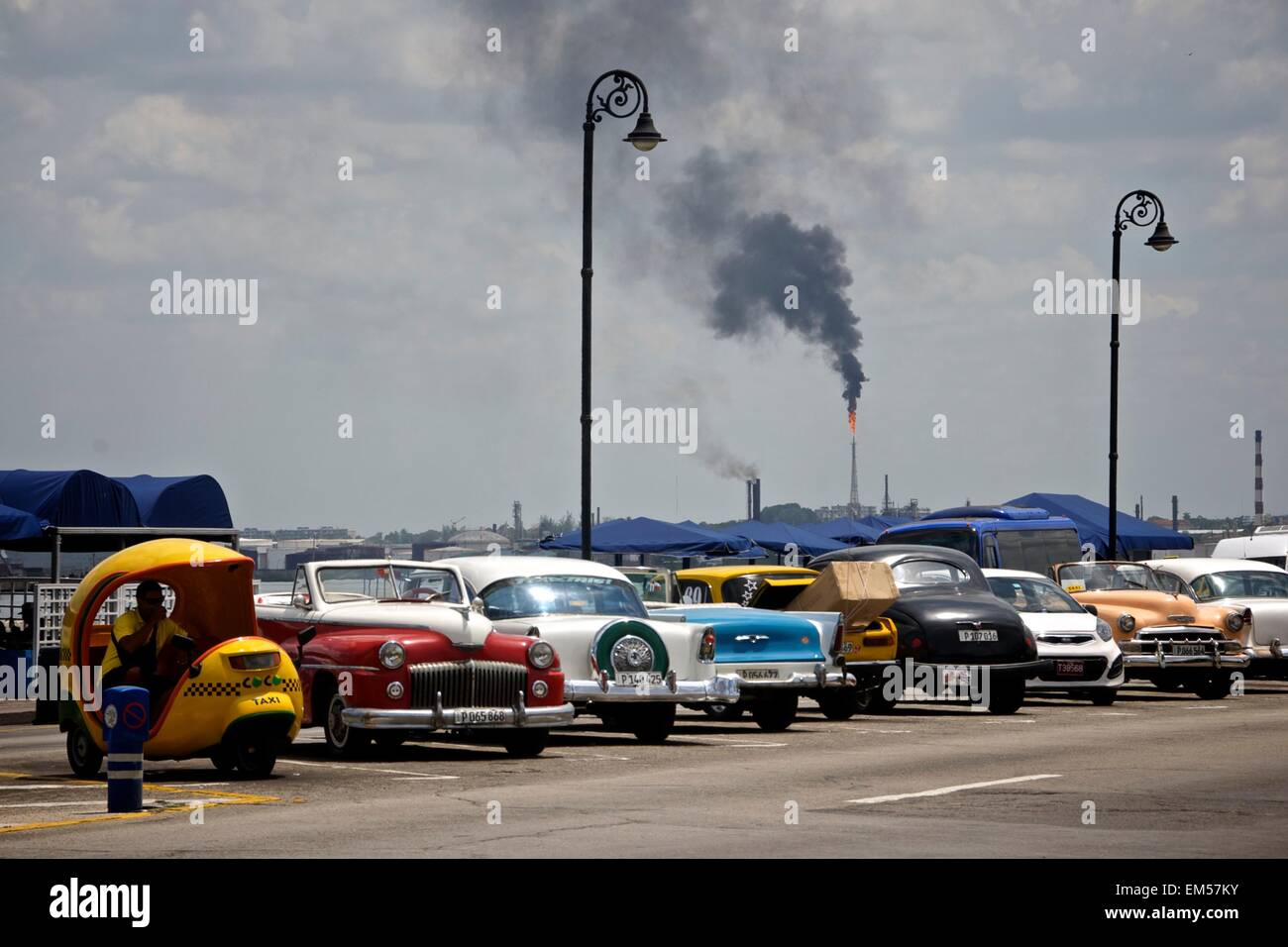 Classic American cars on a Cuban street in Havana with an oil refinery ...