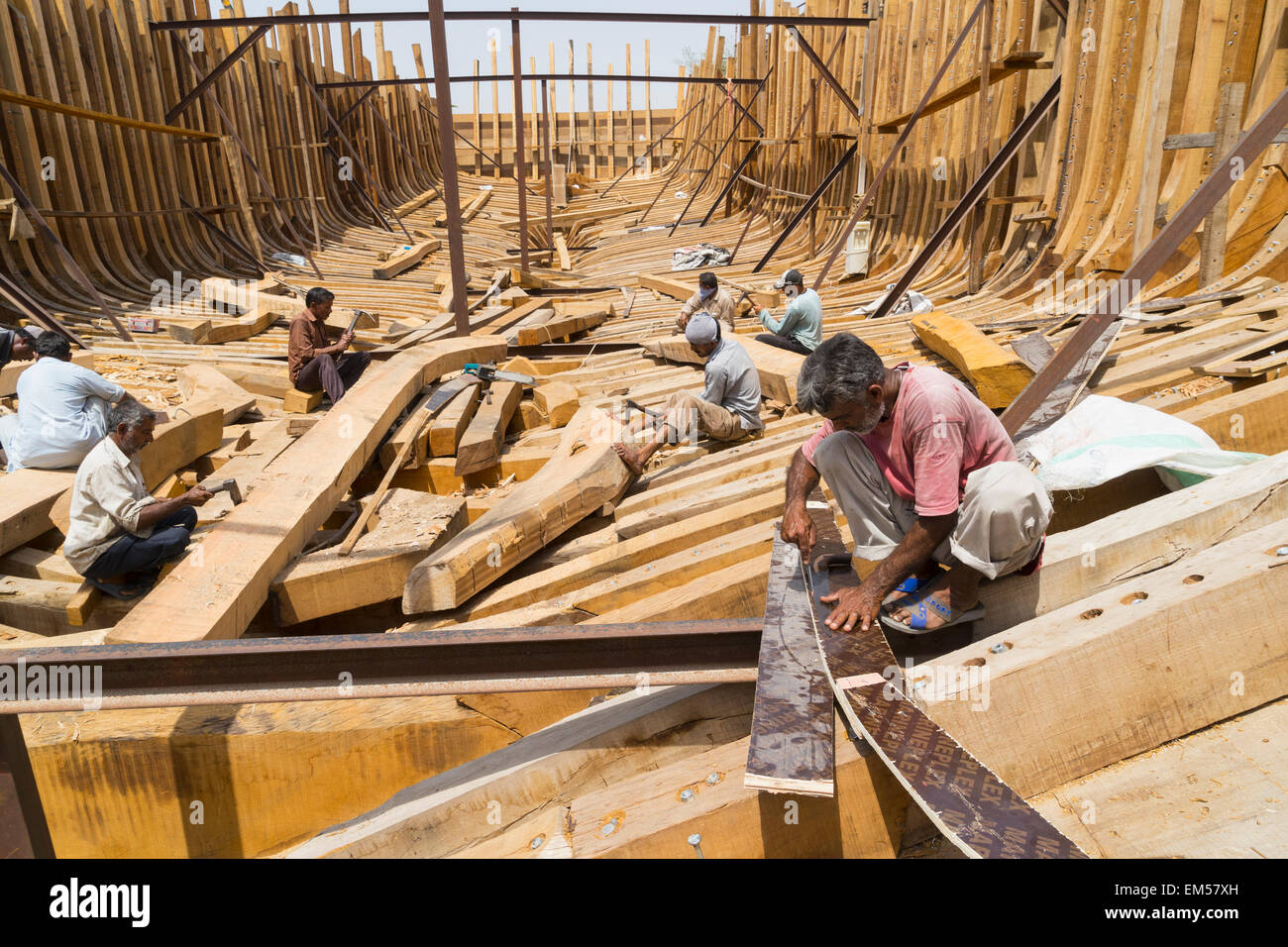 Craftsmen building a traditional wooden dhow cargo ship in shipyard ...