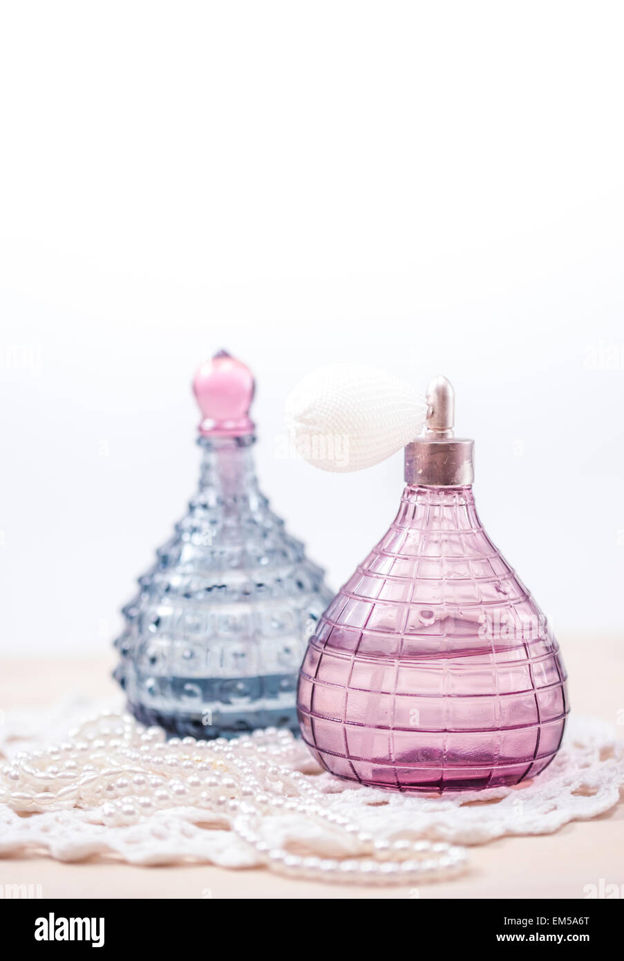 Two glass bottles of female perfume on a white background. Pink toning ...
