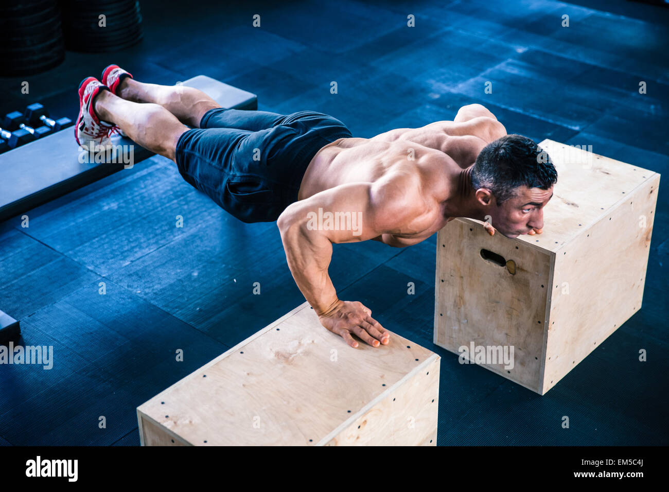 Muscular man doing push ups on fit box and bench at gym Stock Photo - Alamy