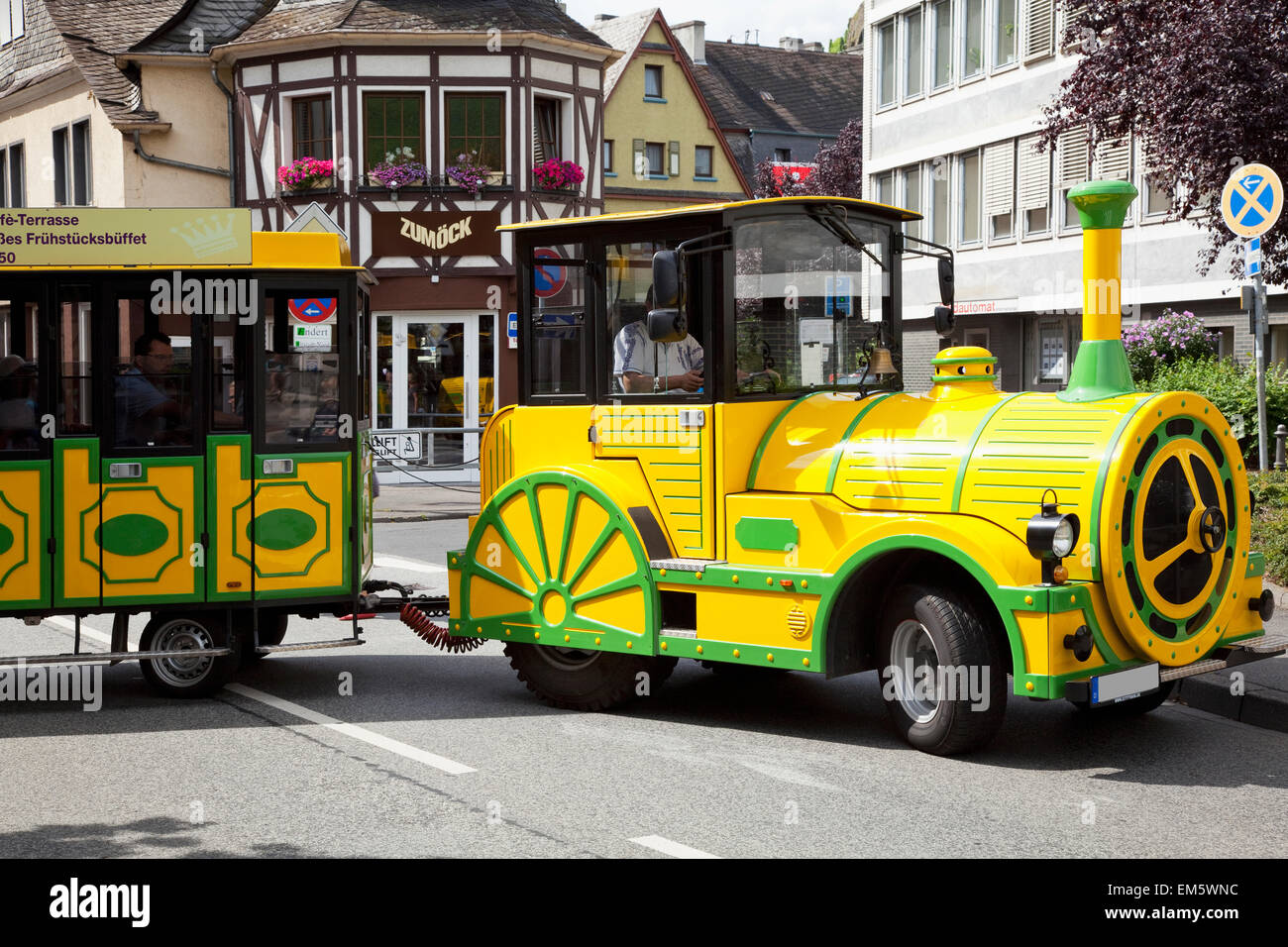Germany, Rheinland-Pfalz, Bright yellow and green tour train in street ...