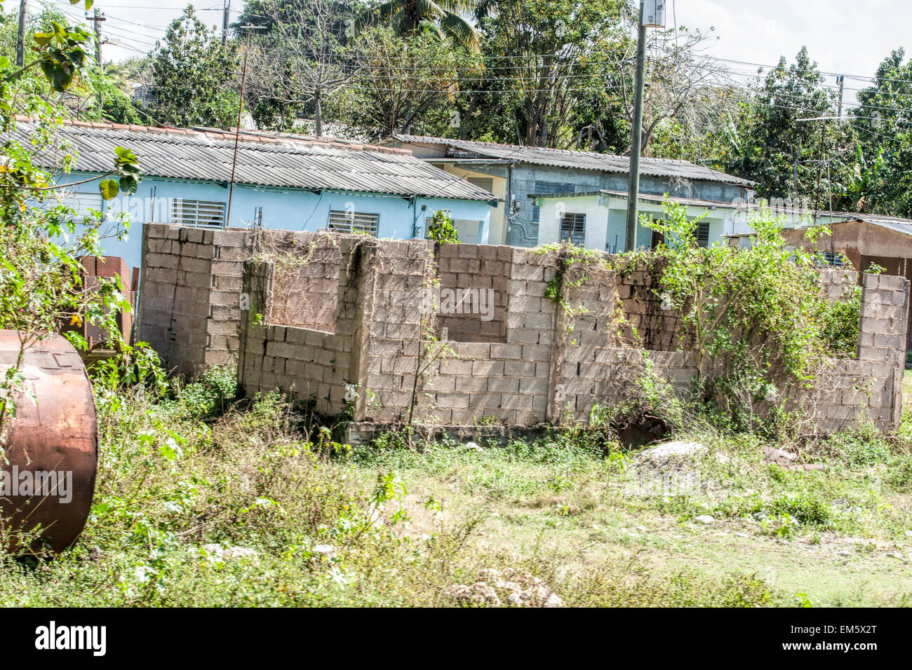 Old half built wall of breeze blocks near a house by the railway track ...