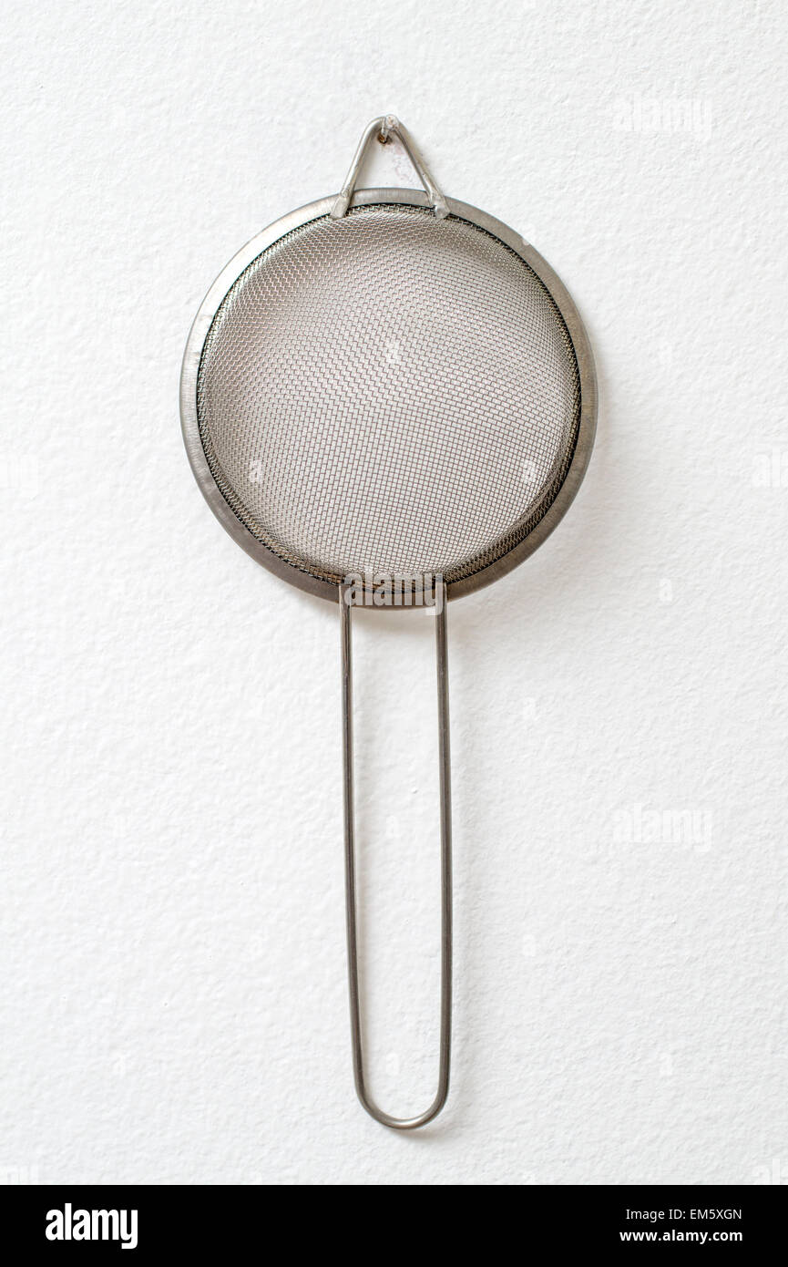 Strainer hanging against white wall as a background Stock Photo - Alamy