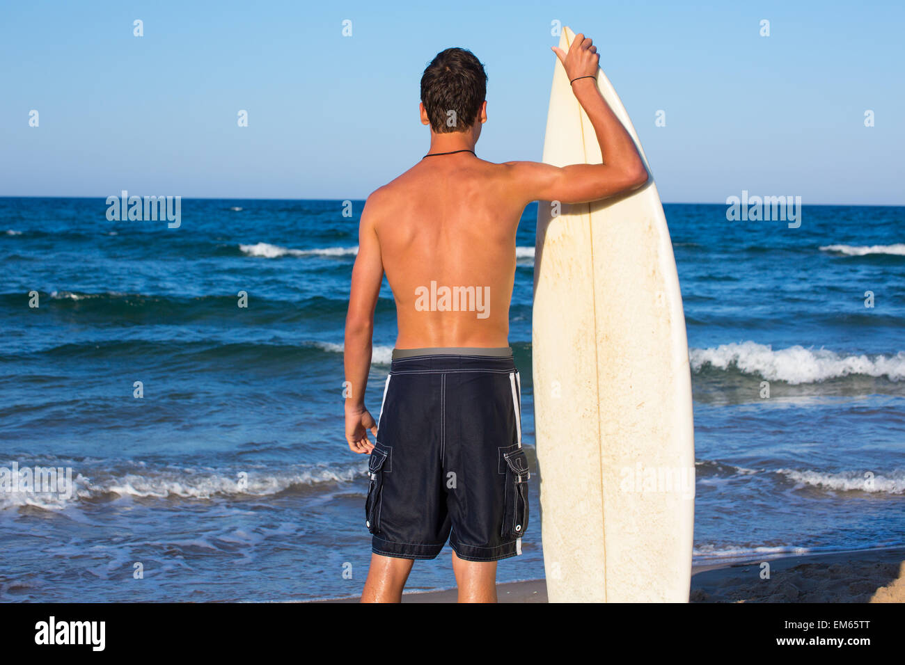 Boy surfer back view holding surfboard on beach Stock Photo - Alamy