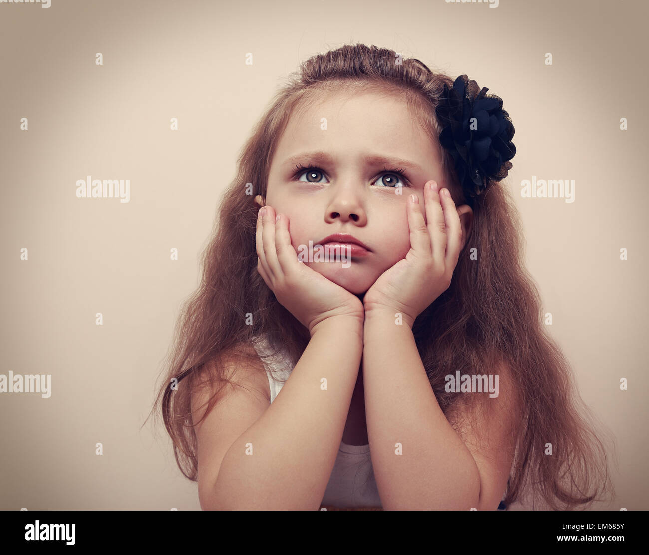 Worried thinking about beautiful long hair girl looking up with hands ...