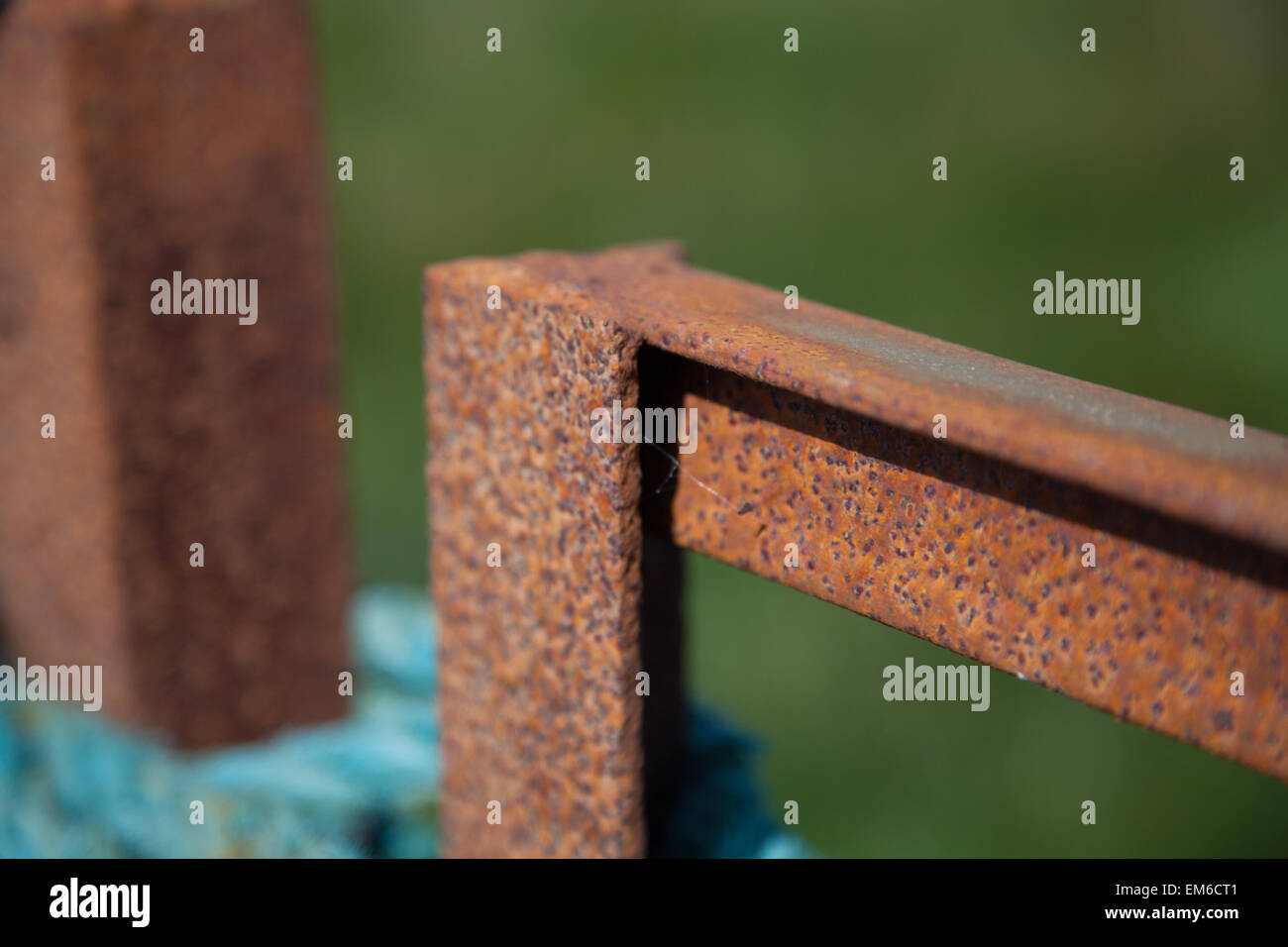 close-up creative shot of a pitted rusty farm gate tied shut with blue ...