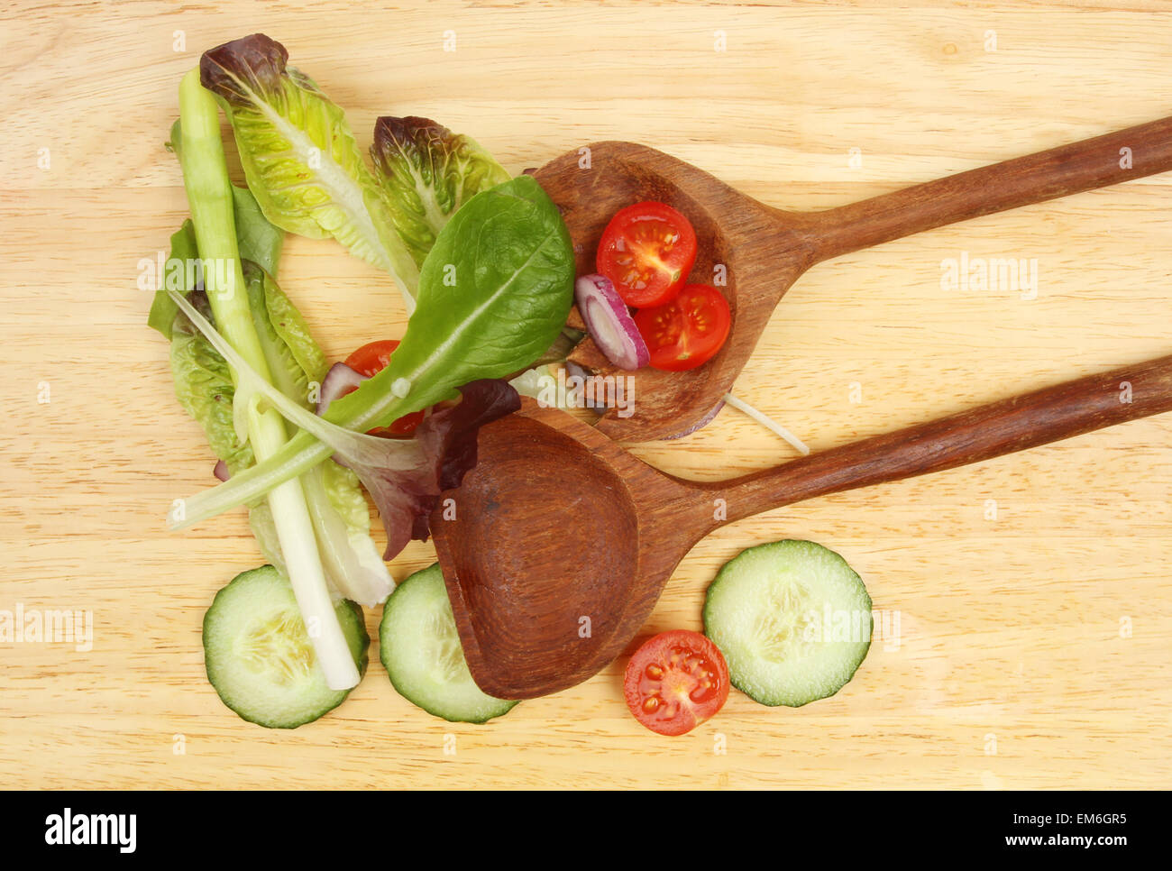 Salad ingredients with salad servers on a wooden board Stock Photo - Alamy