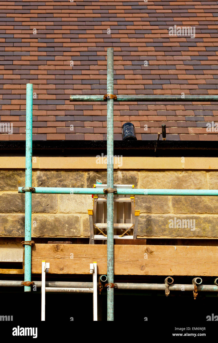 Scaffolding poles next to roof on a building site with new roof tiles ...