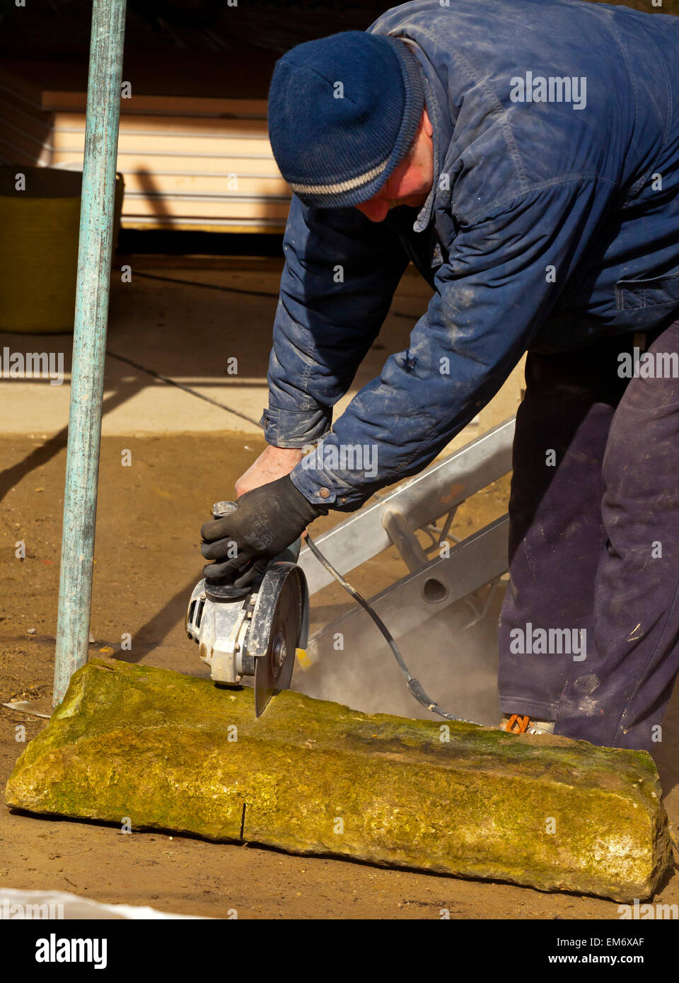 Construction worker on building site using circular saw to cut stone ...