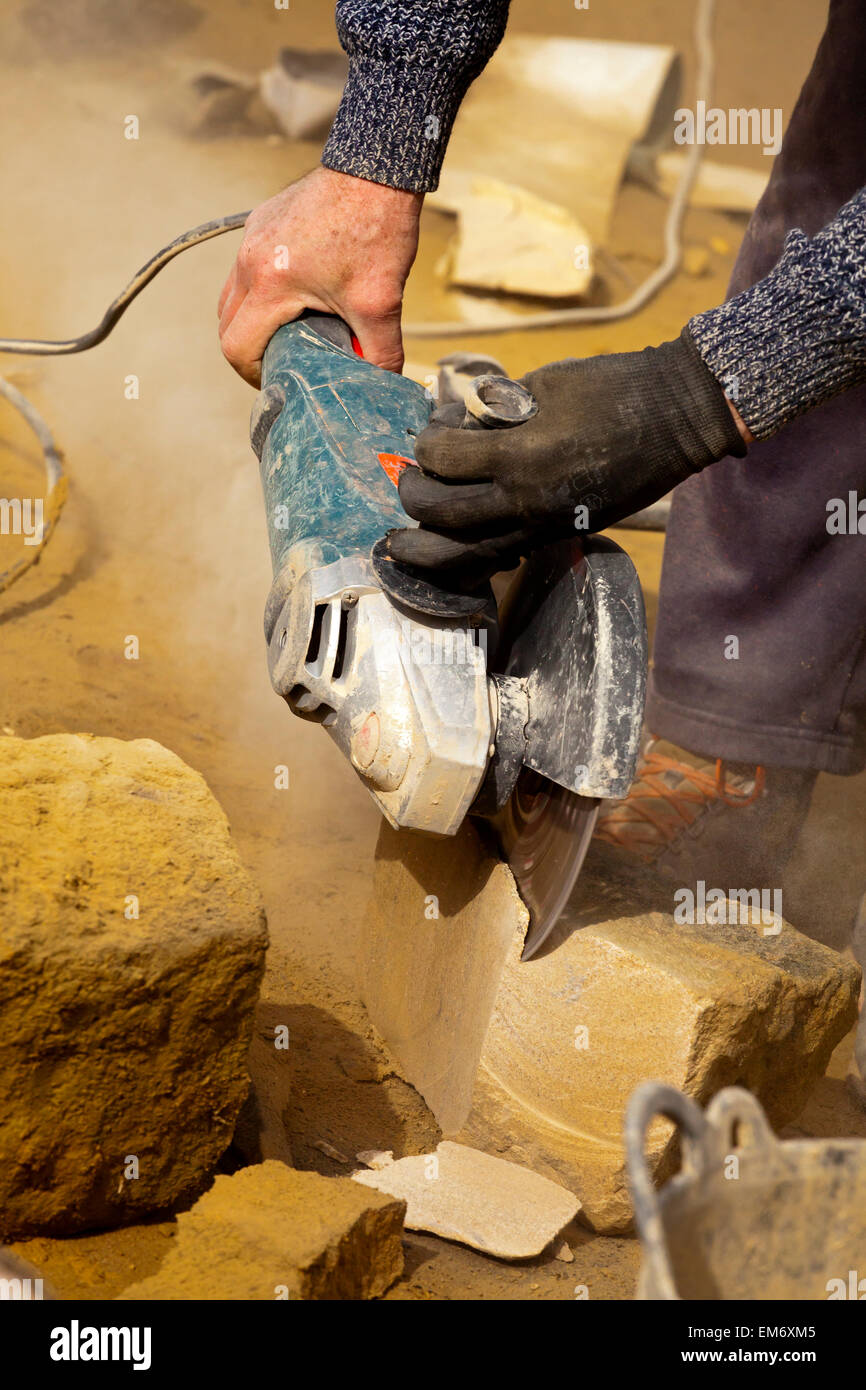 Construction worker on building site using circular saw to cut stone ...
