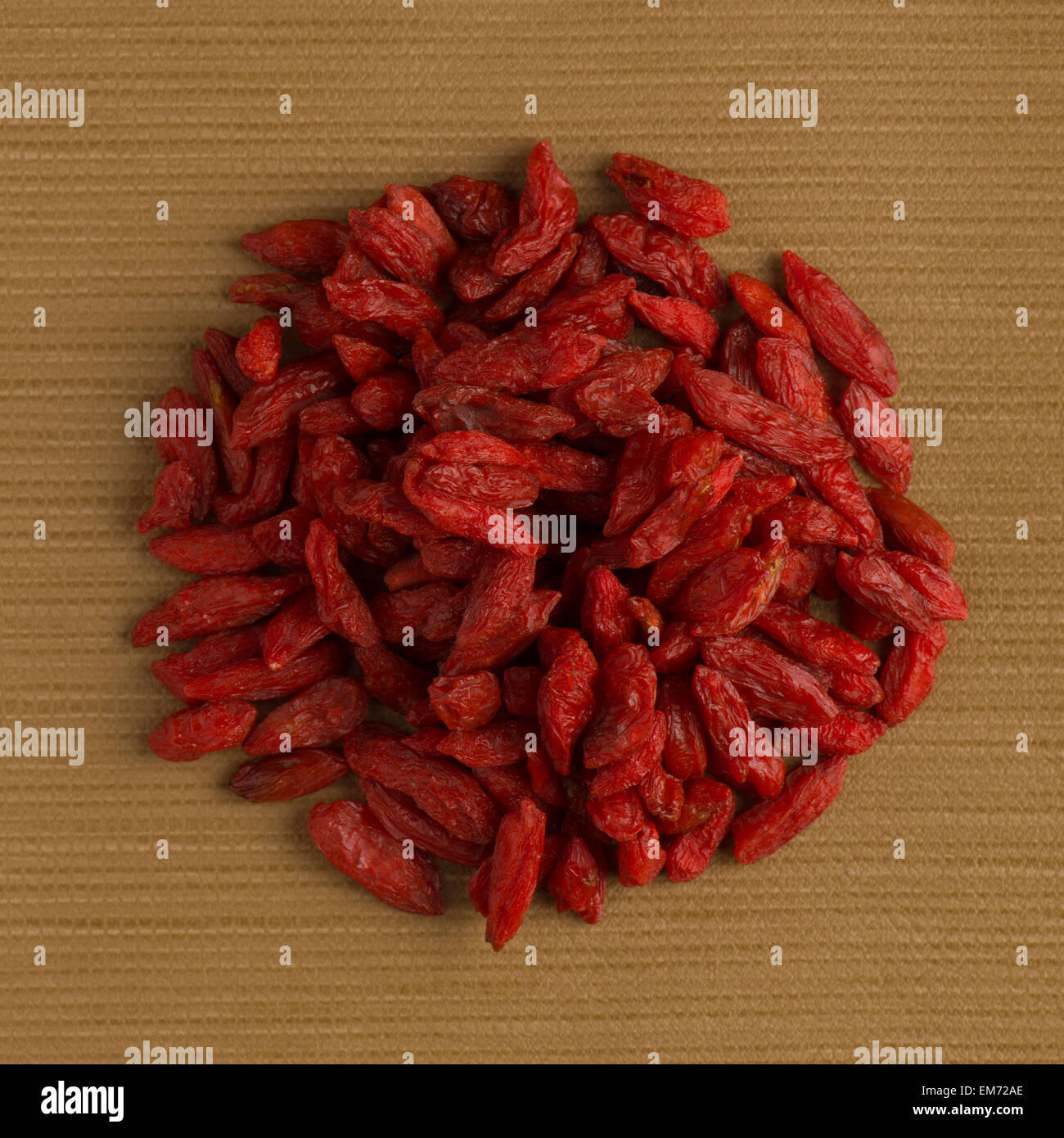 Top view of circle of dry red goji berries against brown vinyl ...