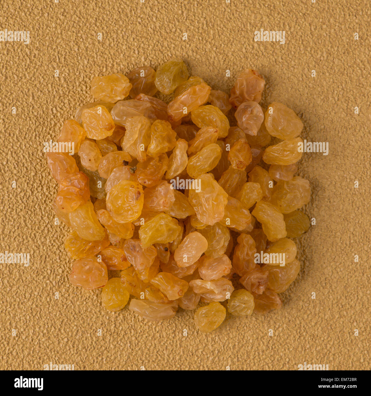 Top view of circle of golden raisins against yellow vinyl background ...
