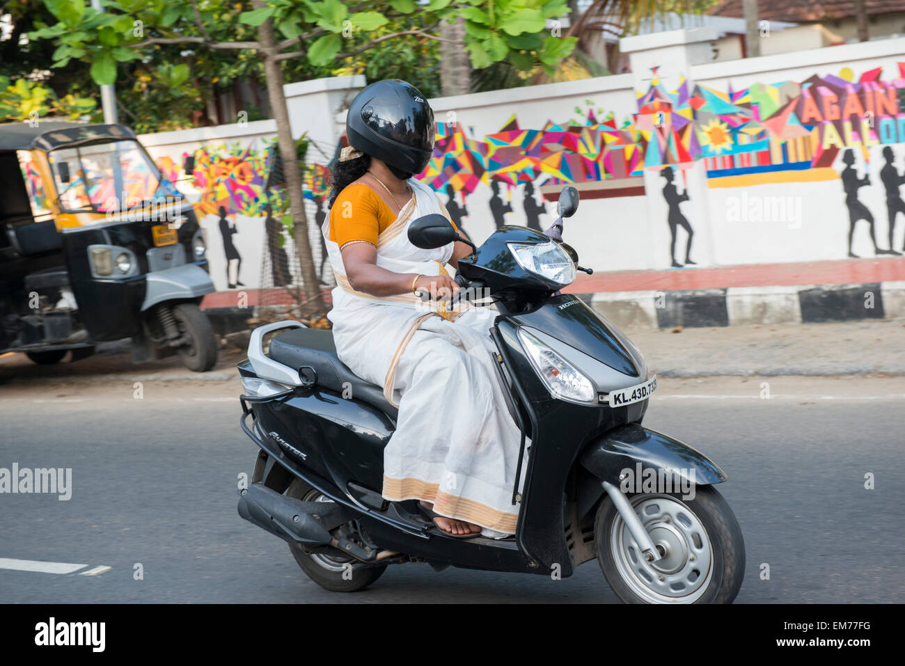 A young woman riding a motorcycle through Fort Kochi, Kerala India ...