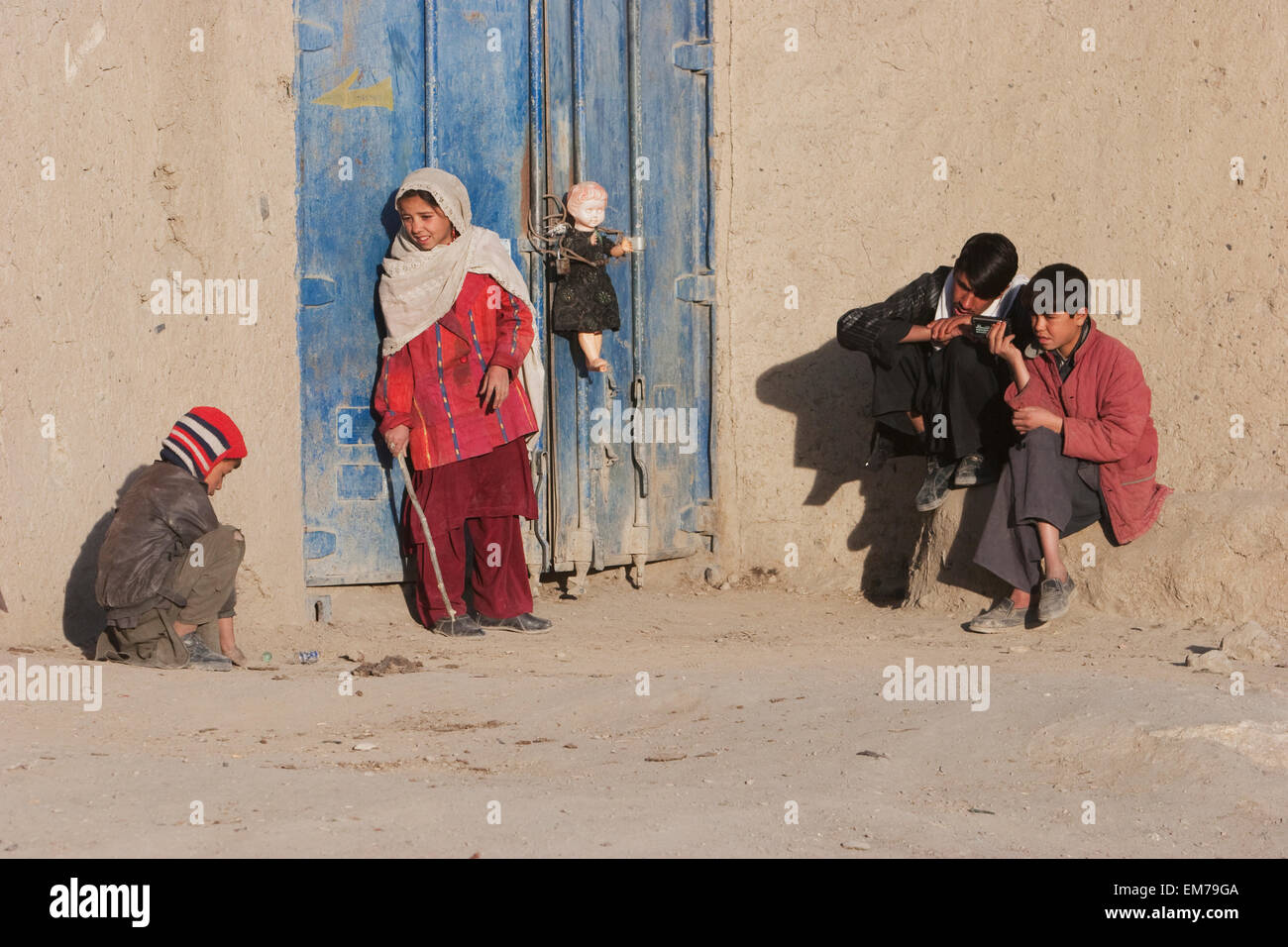 Afghan Girl Standing Next To A Doll Hanging From A Container Door And ...