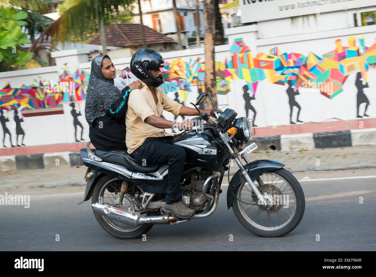 A man and woman riding on a motorbike through Fort Kochi, Kerala India ...