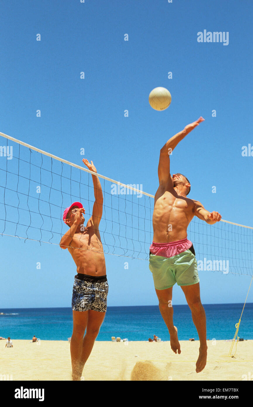Two Men At Volleyball Net, Spiking The Ball At The Beach With Blue Sky ...