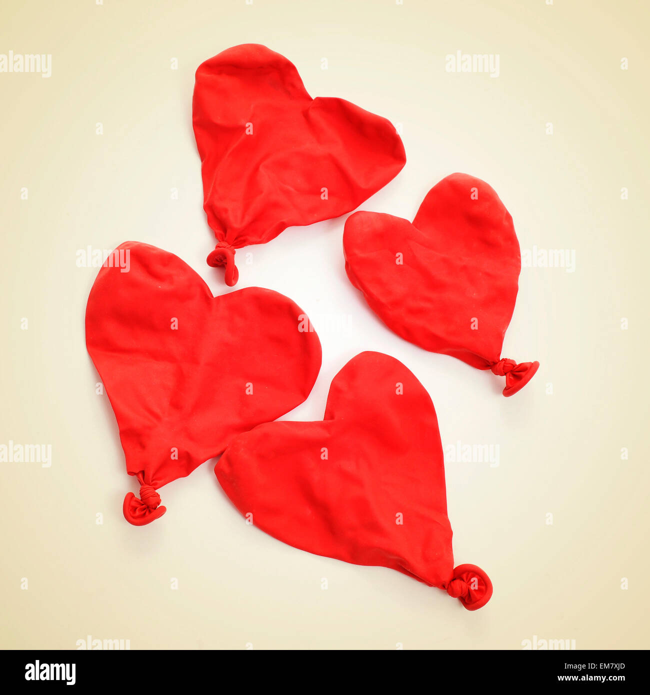some deflated heart-shaped balloons on a beige background, with a retro ...