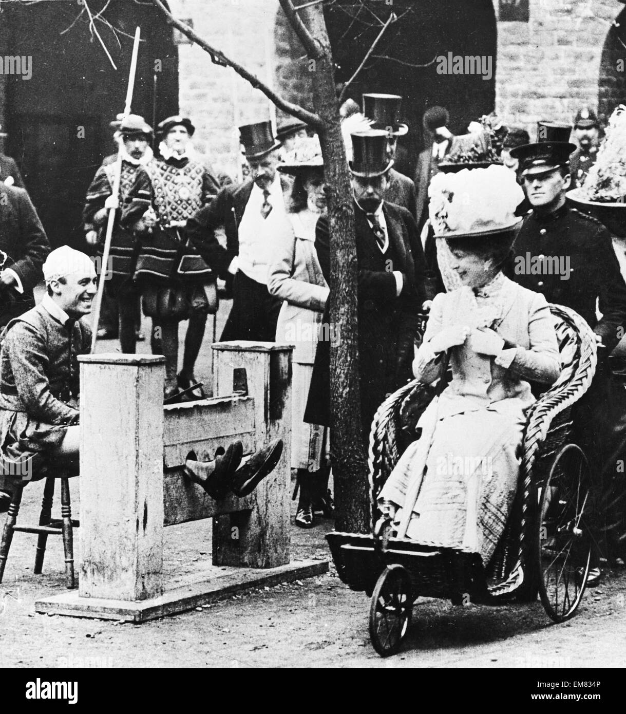 George V and Queen Mary laughing at a man in the stock during a visit ...