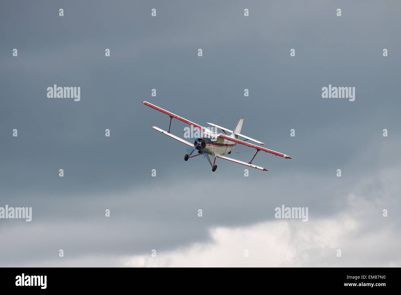Old propeller biplane landing with stormy clouds on the background ...