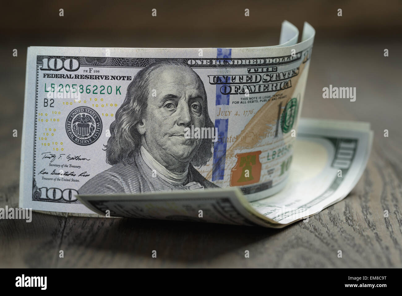 new hundred dollar bills on wood table Stock Photo - Alamy