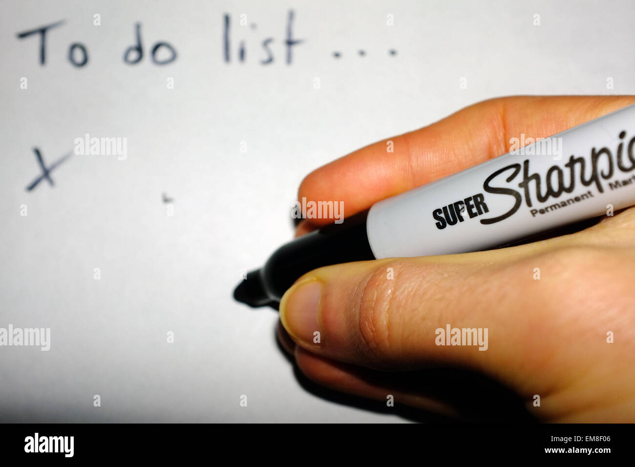 A white hand holding a Sharpie pen writing a 'To do list' on a sheet of ...