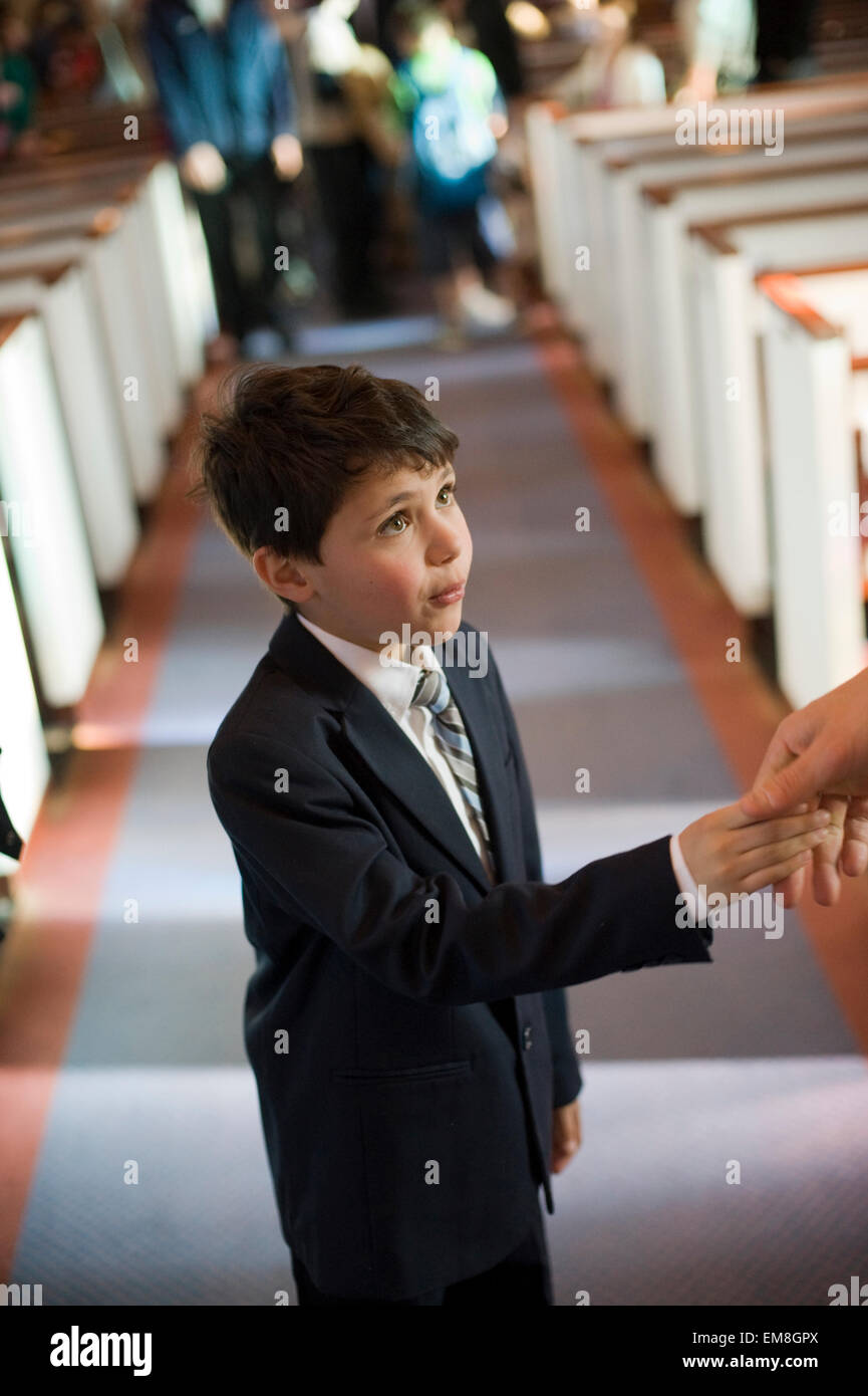 Seven year old Hispanic boy shakes the hand of priest in church after ...