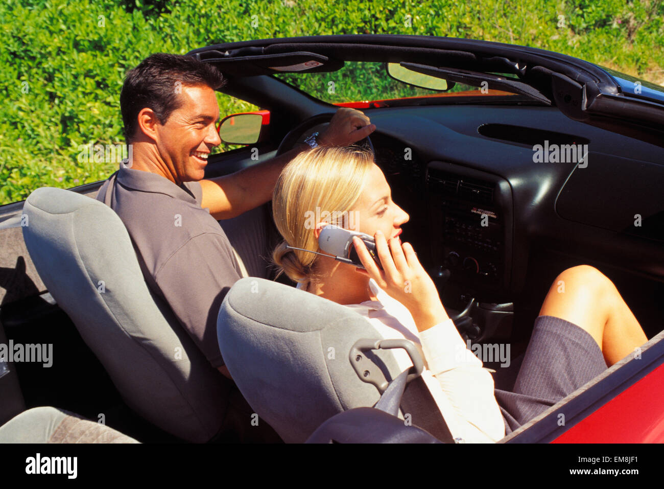 Couple In Convertible, Girl On Mobile Phone Stock Photo - Alamy