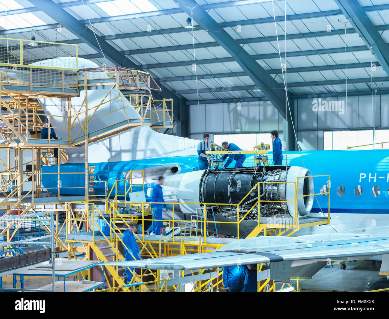 Engineers removing jet engine from aircraft in aircraft maintenance ...