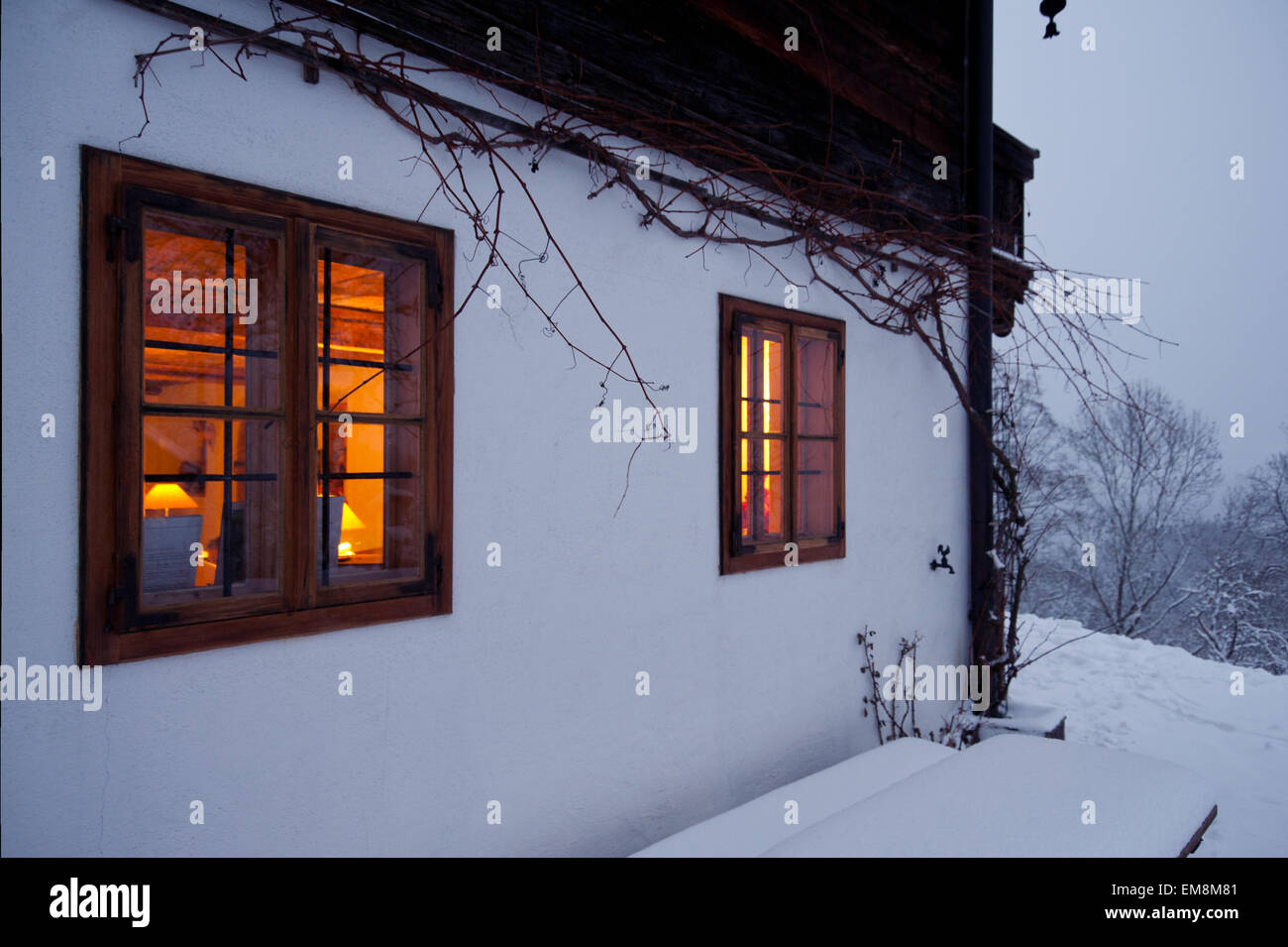 illuminated windows of alpine house in winter evening Stock Photo - Alamy