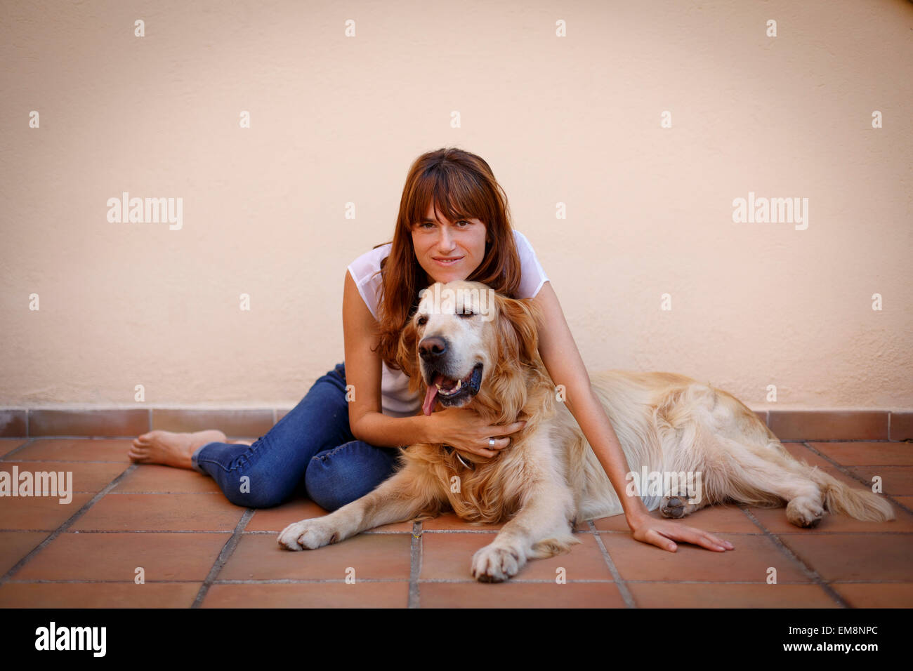 Portrait of mid adult woman petting dog on kitchen floor Stock Photo ...