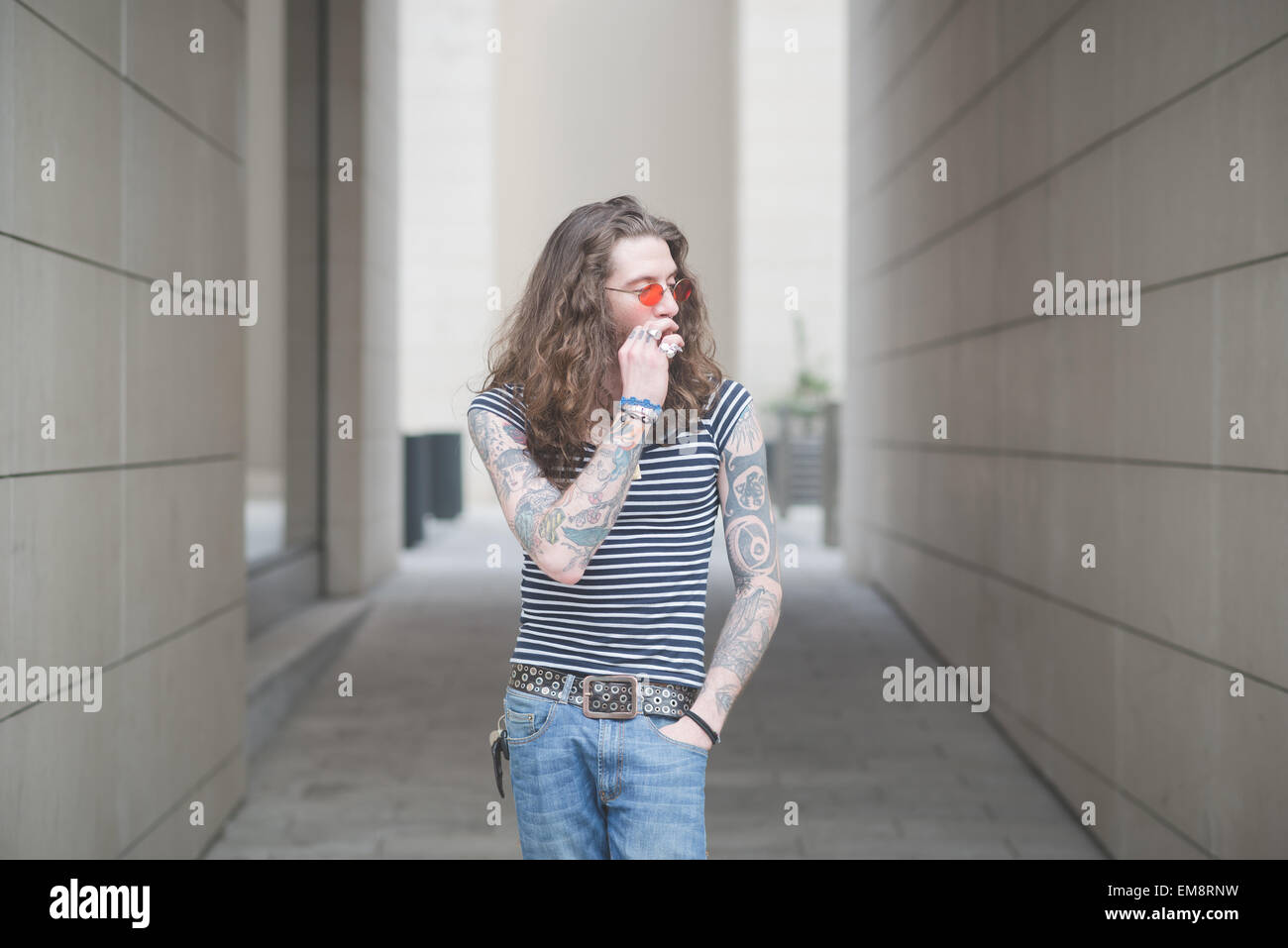 Young male hippy smoking cigarette in city alley Stock Photo - Alamy