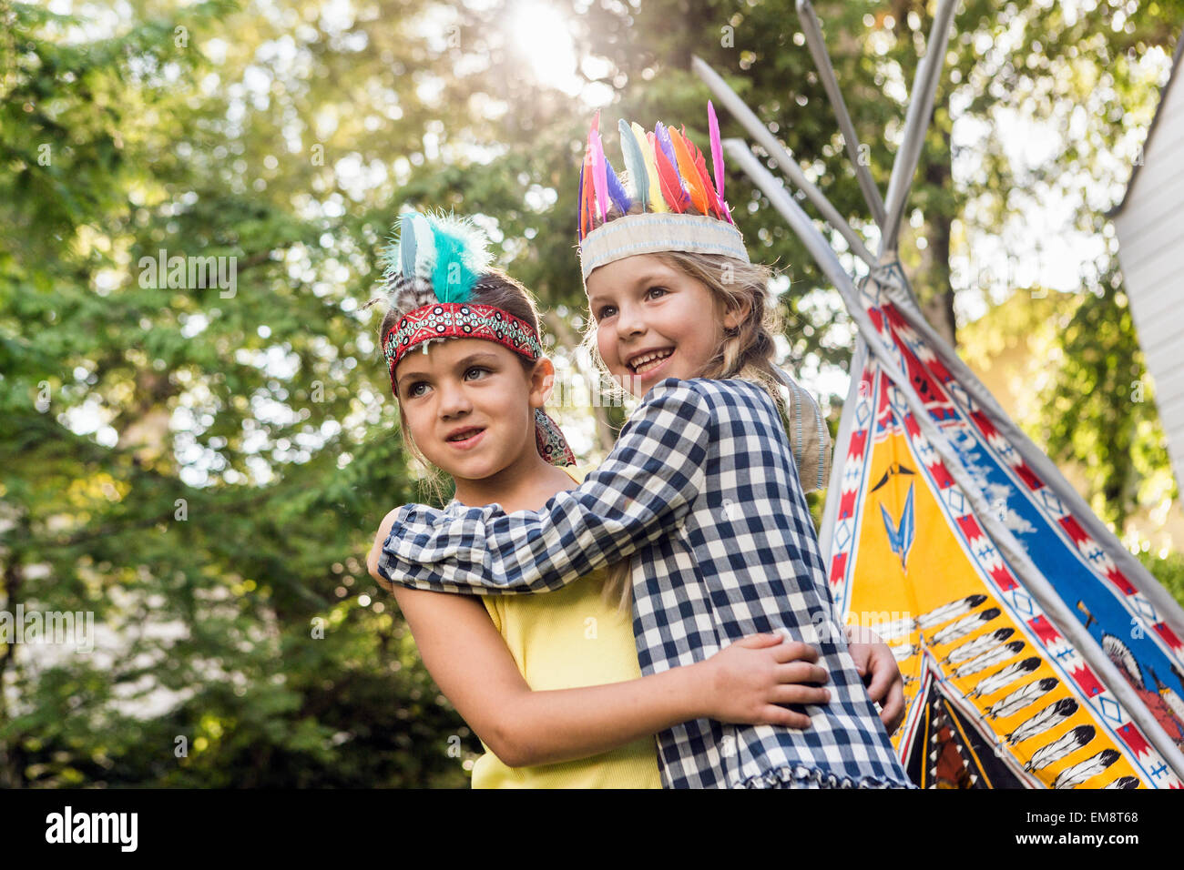 Two girls in native American headdress hugging in garden Stock Photo ...