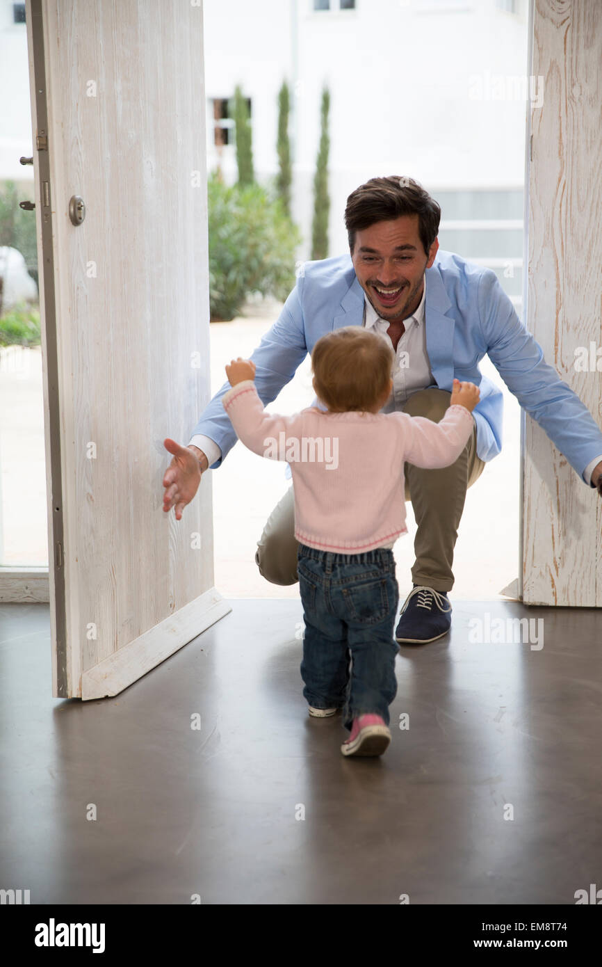 Female toddler running to fathers arms at front door Stock Photo - Alamy