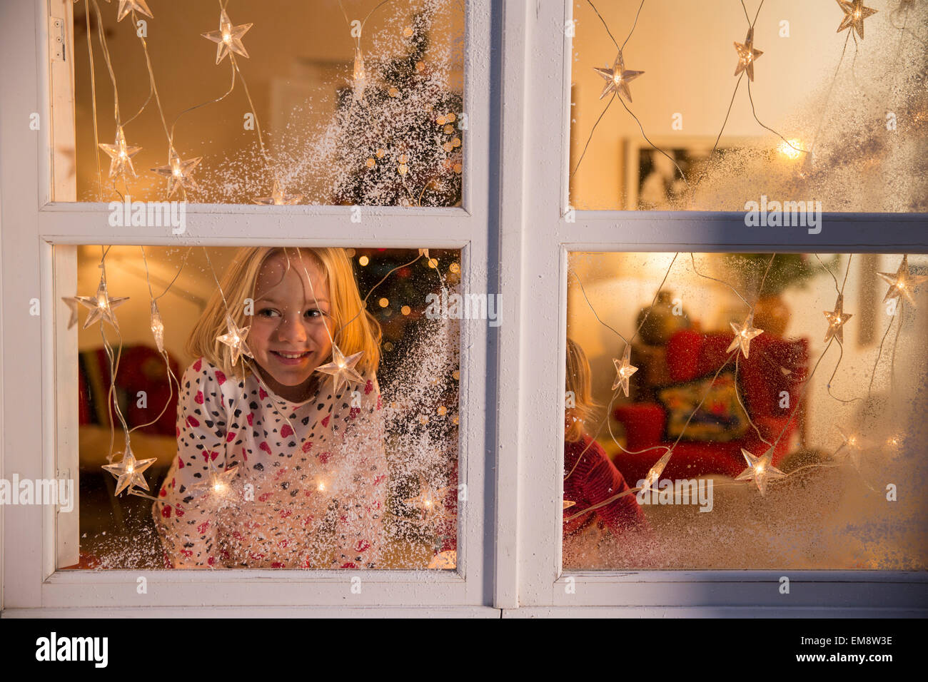 Girl looking out of window with Christmas decorations Stock Photo - Alamy